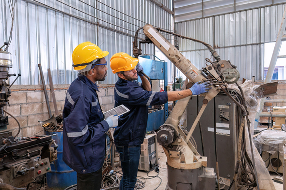 Factory maintenance engineer working with old defected robotic arm in ...