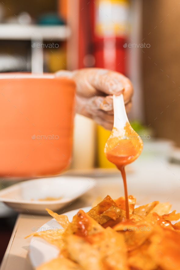 Vertical photo of the hand of a cook spreading sauce on nachos Stock ...