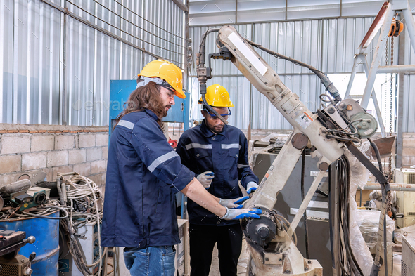 Factory maintenance engineer working with old defected robotic arm in ...