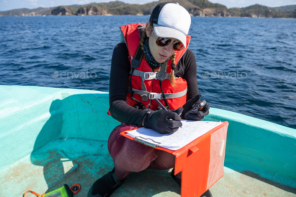 Equipped marine biologist writing notes on a boat Stock Photo by riderfoot