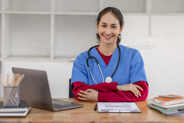 Portrait of Asian female doctor sitting on work desk and smiling ...
