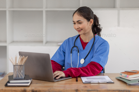 Portrait of Asian female doctor sitting on work desk and smiling ...