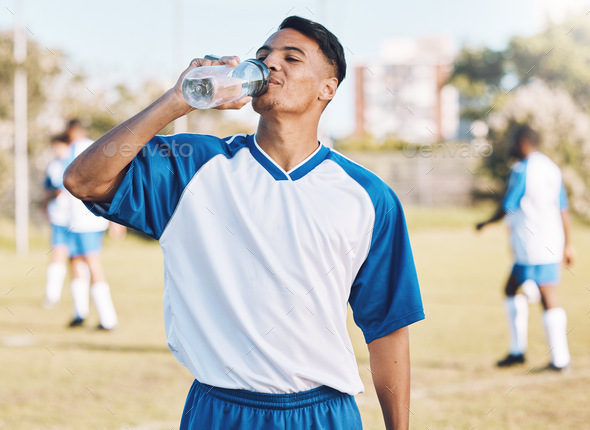 Drinking water, break and soccer player on a sports field resting after ...