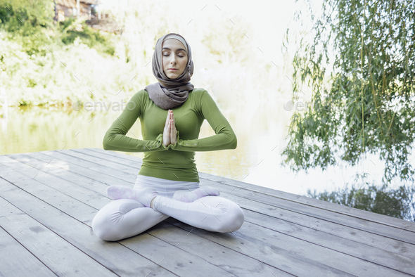 Muslim young girl in a hijab is doing yoga asana in the park Stock ...