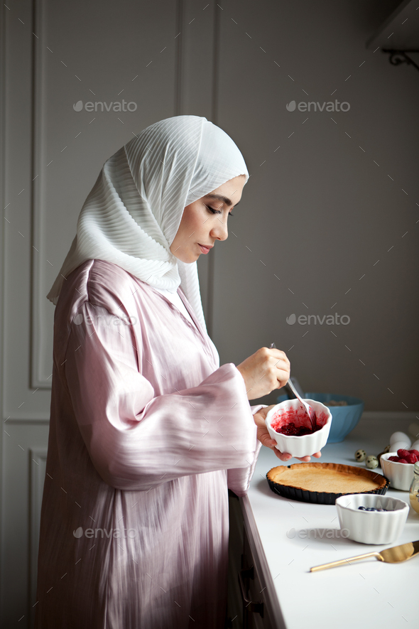 Side view portrait Muslim woman cooks dessert cake at kitchen, arabian ...