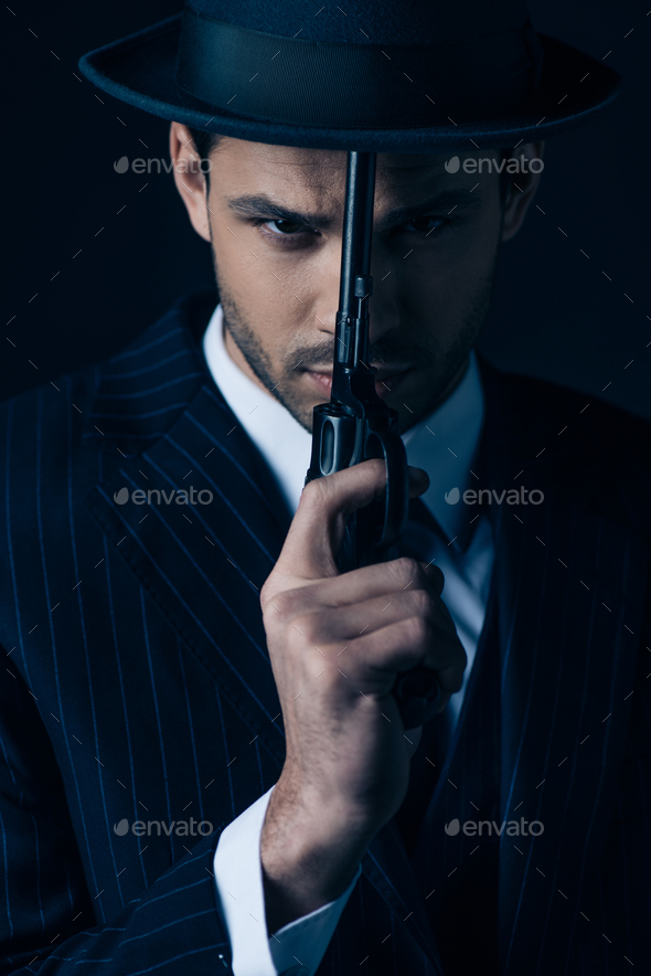 Gangster holding gun in front of face on dark blue Stock Photo by ...