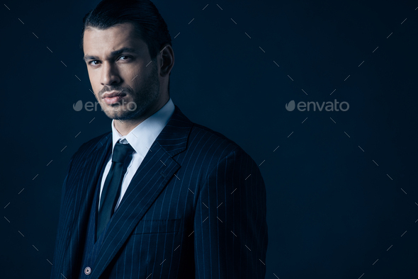 Elegant mafioso looking at camera on dark blue background Stock Photo ...
