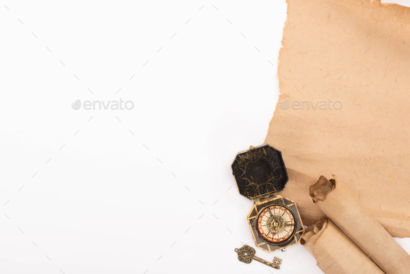 top view of vintage compass, key and aged parchment paper isolated on ...