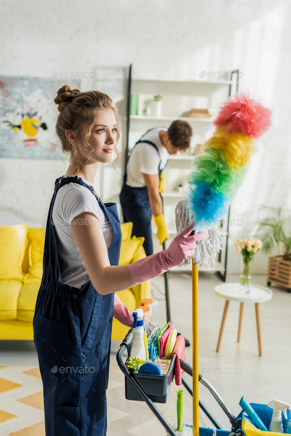 selective focus of attractive cleaner holding duster brush near ...