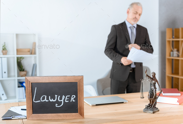 lawyer workplace with chalkboard and themis statue with blurred man on ...