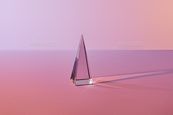 crystal transparent pyramid with light reflection on pink background ...