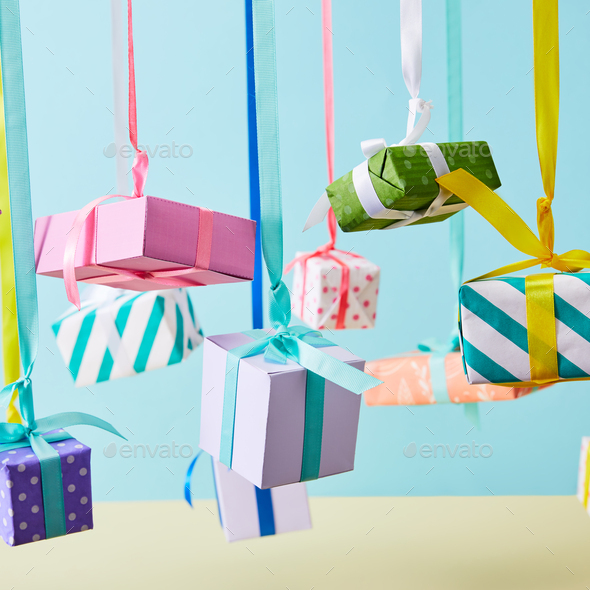 festive colorful gift boxes hanging on ribbons on blue background Stock ...