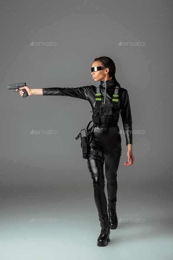 attractive futuristic african american woman in glasses aiming gun on ...
