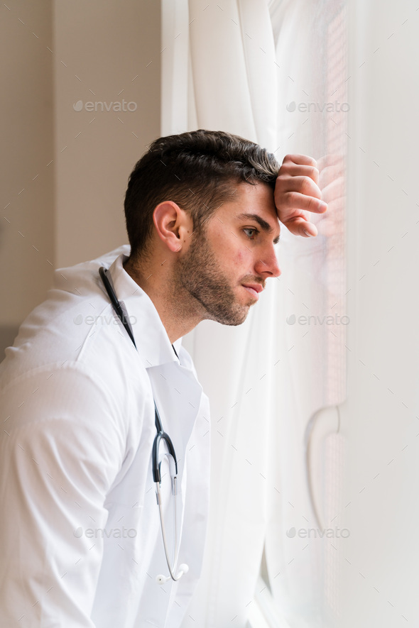 sad doctor standing near window has lost a patient Stock Photo by ...