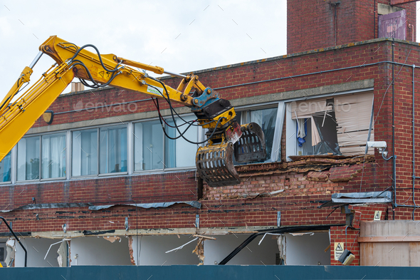 Demolition of an old building with a long reach machine hydraulic jaw ...