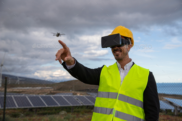 An engineer pilots a drone wearing VR headsets in a field of solar ...