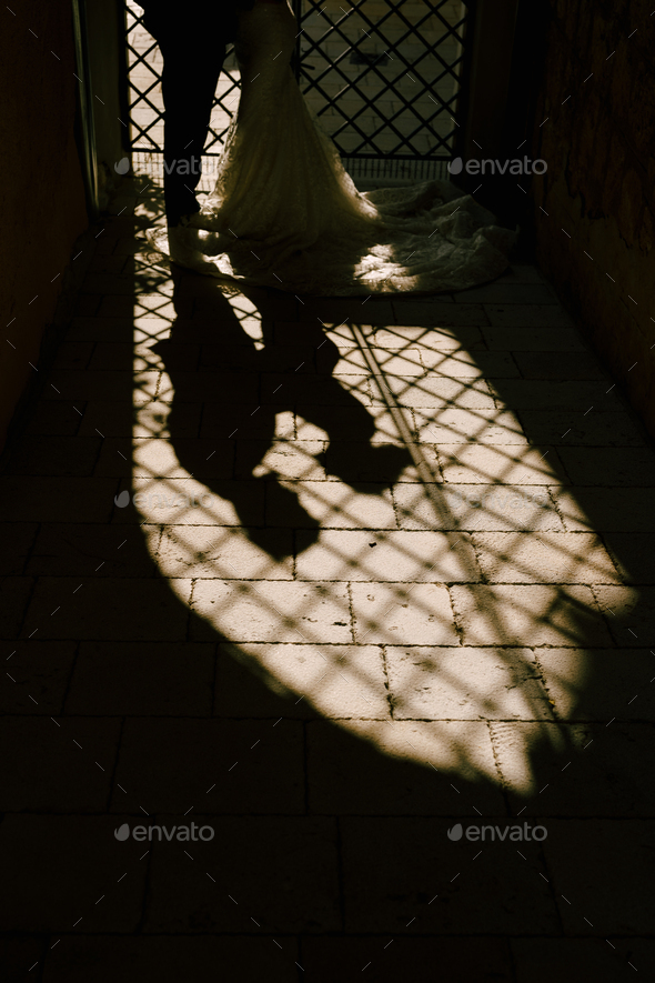 Shadows of the bride and groom on the cobblestones behind the mesh door ...