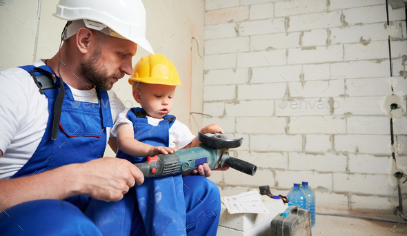 Man and child construction workers using electric angle grinder. Stock ...
