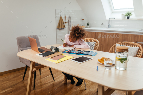 Afro girl doing homework while sitting at the table Stock Photo by ...