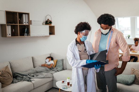 Doctor having consultation with man whose son is sick and lying on bed ...