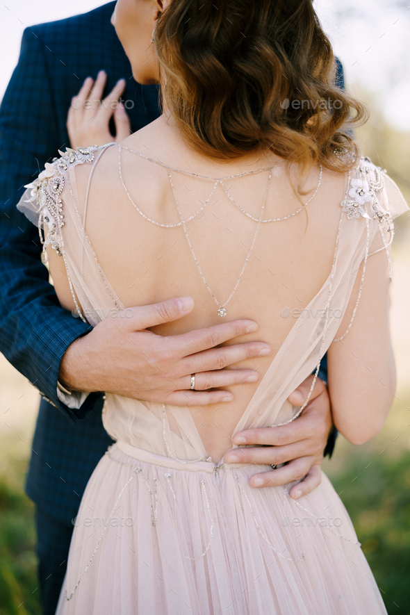 Groom hands hug bride lower back. Back view. Close-up Stock Photo by ...