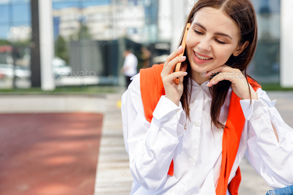 Happy female student calling by phone after classes outdoors. Stock ...