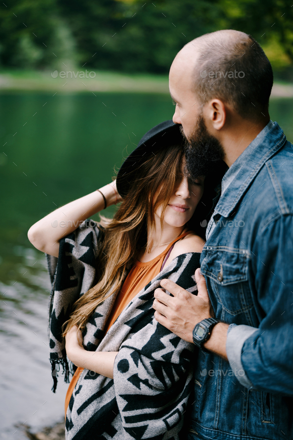 Man hugs the shoulders of a pregnant woman near the lake. Portrait ...