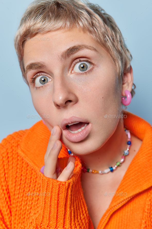 Close up shot of shocked short haired woman stares with bugged eyes ...