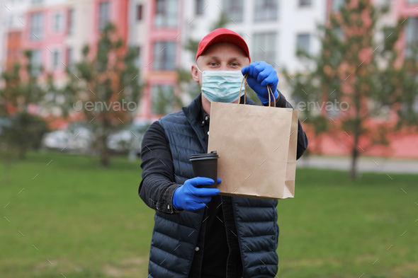 Delivery man in red cap, face medical mask, gloves hold take away paper ...