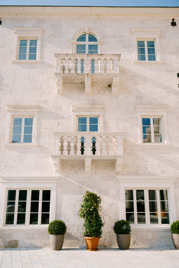 White stone building facade with balconies and flowerpots on a tiled ...