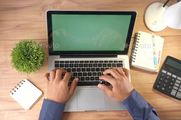 top view pf young man using laptop with blank screen on office desk ...