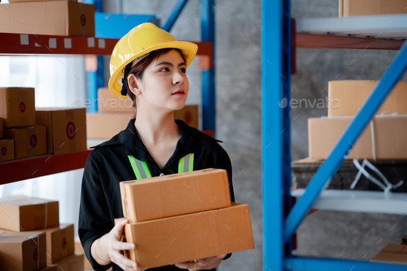 Asian female worker wearing safety clothing is in a warehouse, she is ...