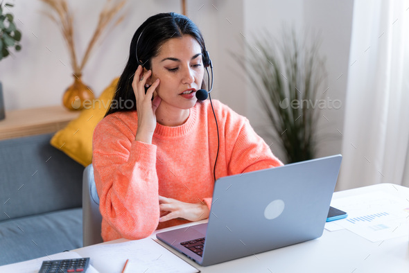 Young woman with laptop talking while working on laptop at home Stock ...