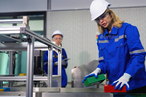 Automation girls engineer in factory testing logistic robot arm picking ...