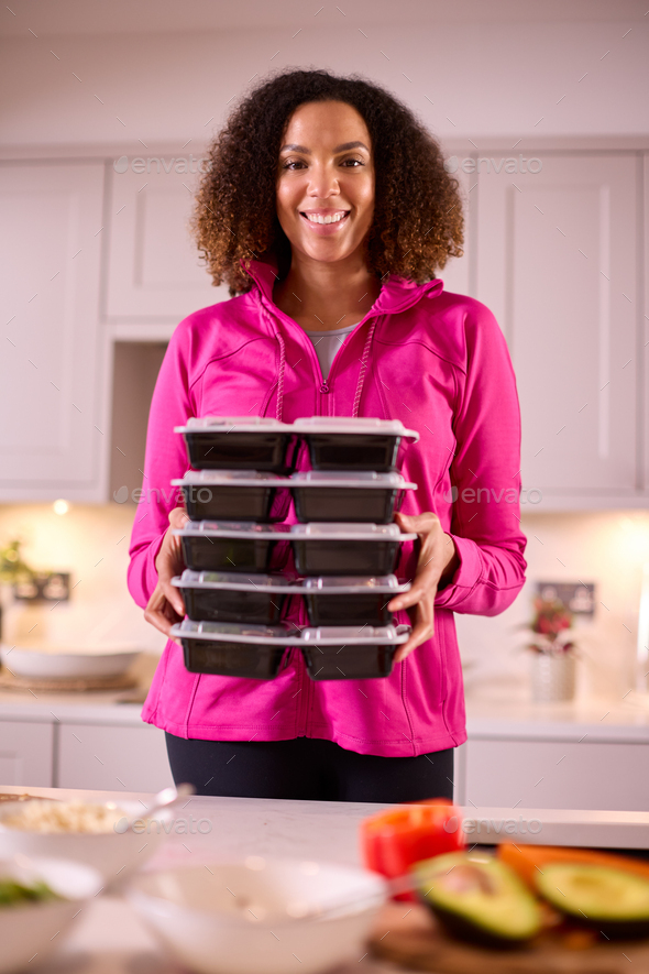Portrait Of Woman In Kitchen Wearing Fitness Clothing Making Batch Of ...