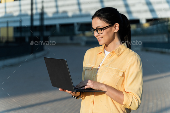 Smiling positive woman holding laptop and typing. Blogger making posts ...