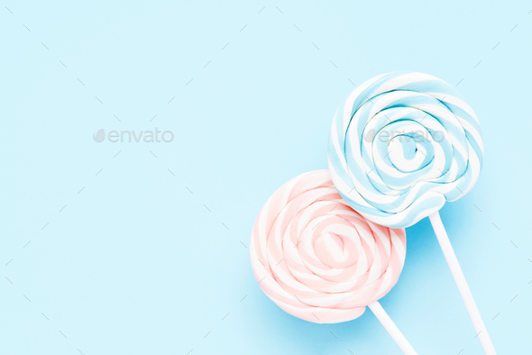 Pink and blue lollipops on a white stick on a light blue background ...