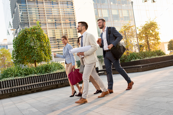 Group of business people walking outside in front of office buildings ...