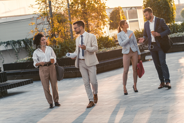 Group of business people walking outside in front of office buildings ...