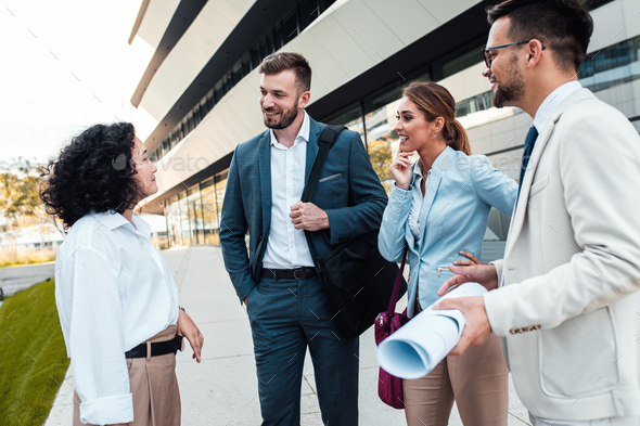 Coworkers standing outside in front of office buildings discuss about ...