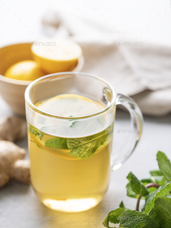 Herbal tea with fresh lemon, mint and ginger on a light background with ...