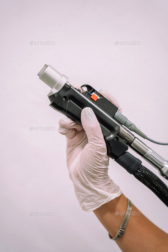 Close up shot of gloved hand with the laser hair removal machine's ...