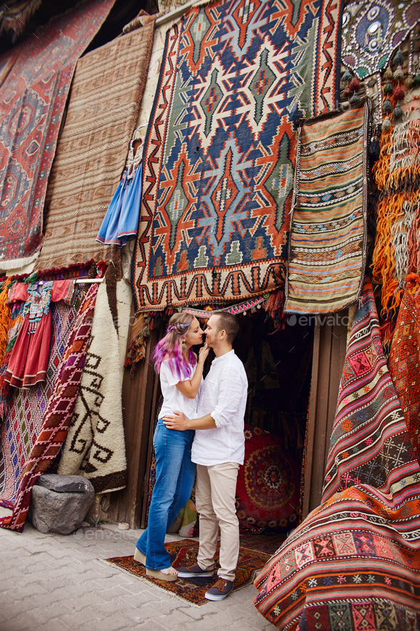 Couple in love buys a carpet and handmade textiles at an oriental ...