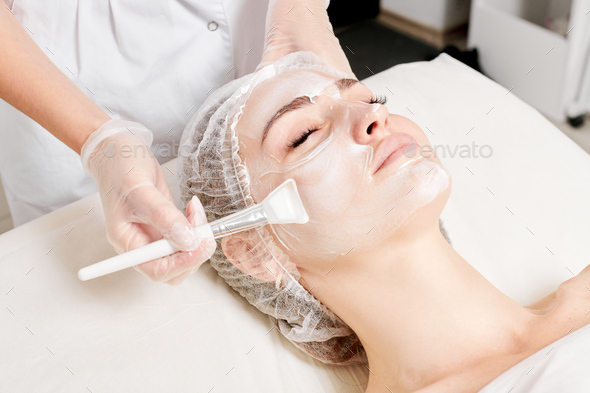Cosmetologist applies cream mask on woman face for rejuvenation face ...
