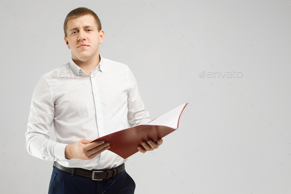 Young man with an open folder in his hands isolated on a light ...