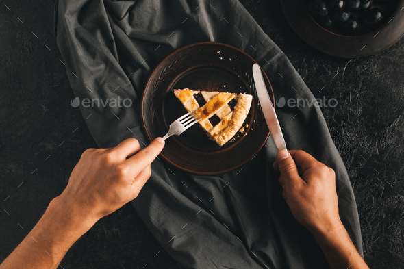 partial view of male hands holding silverware with piece of berry pie ...