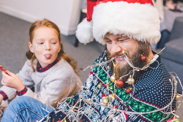 funny daughter and angry father in santa hat tied up with christmas ...