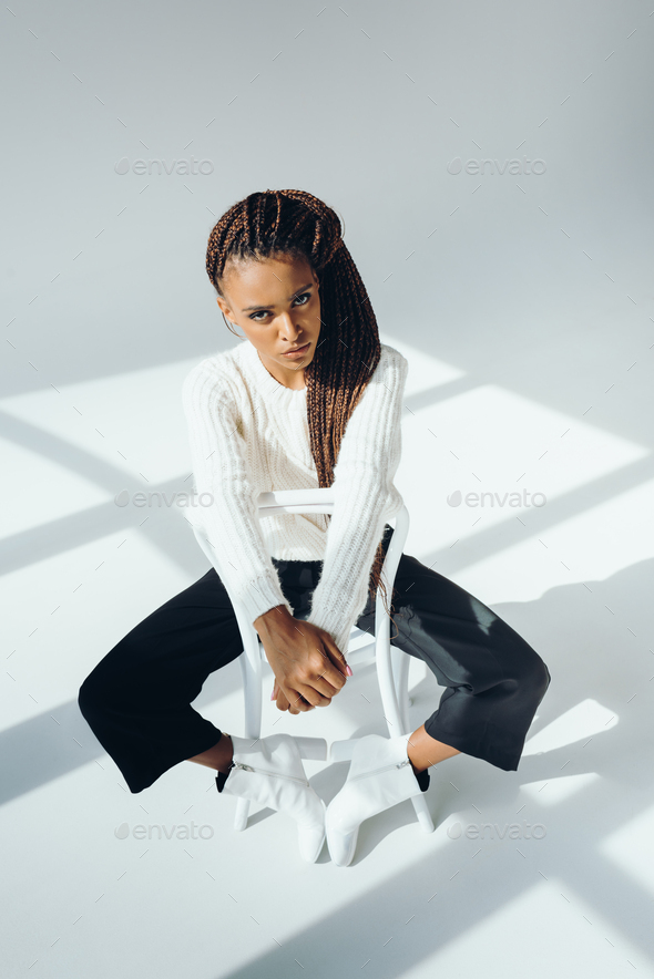high angle view of stylish african american woman sitting on chair and ...