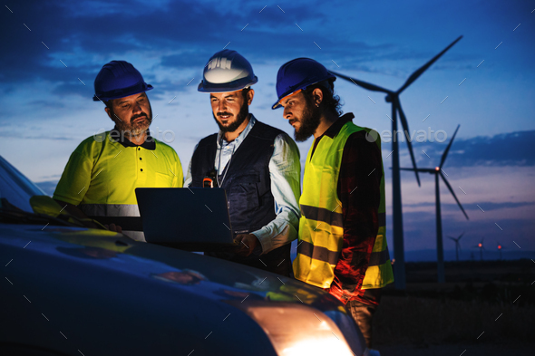 Team work of three renewable energy engineers with helmets and ...