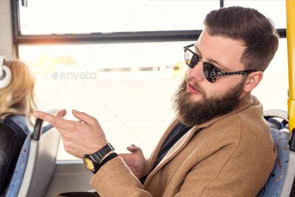 side view of man in sunglasses pointing away while riding in public ...